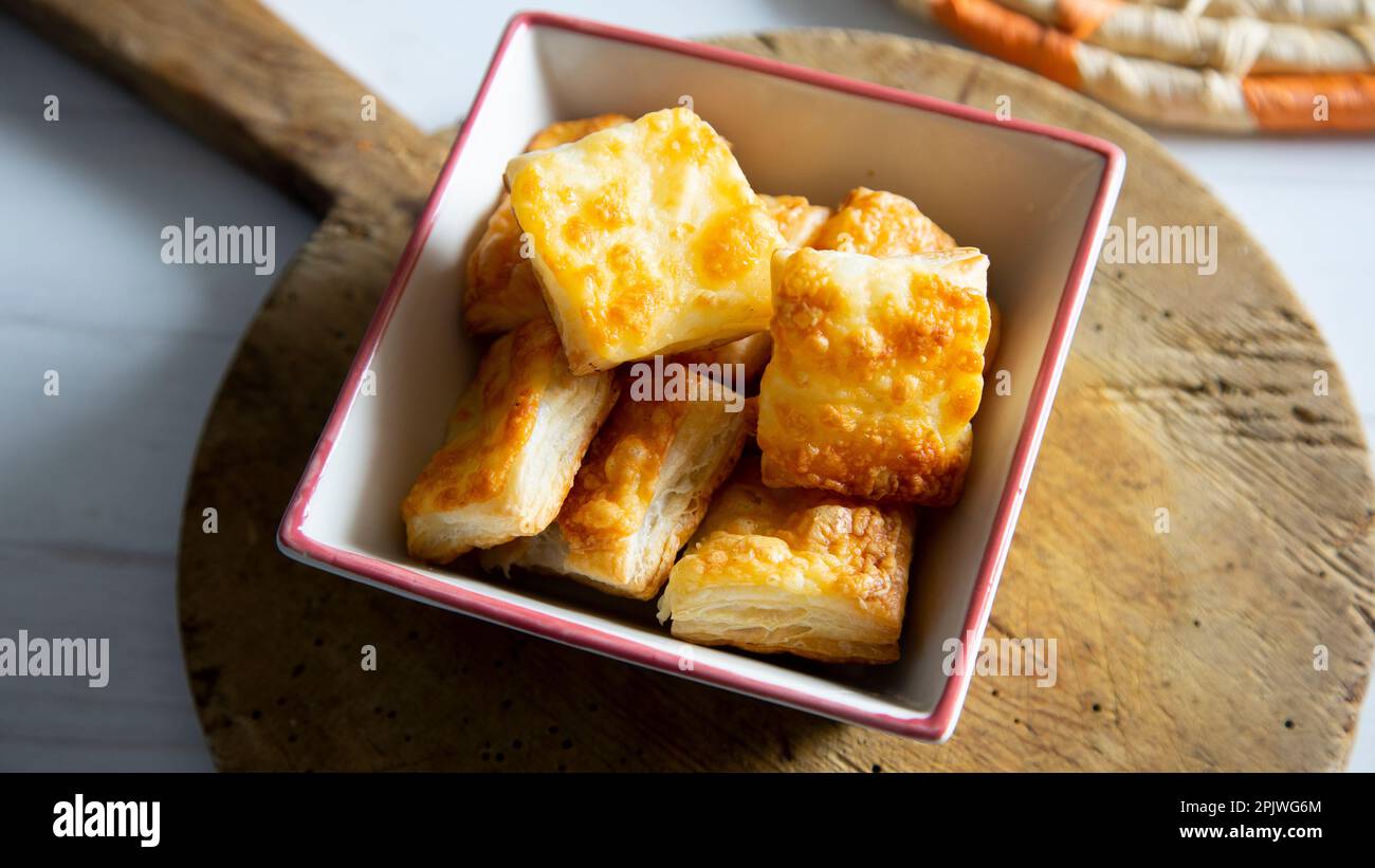 Small, square puff pastries with gratin cheese Stock Photo - Alamy