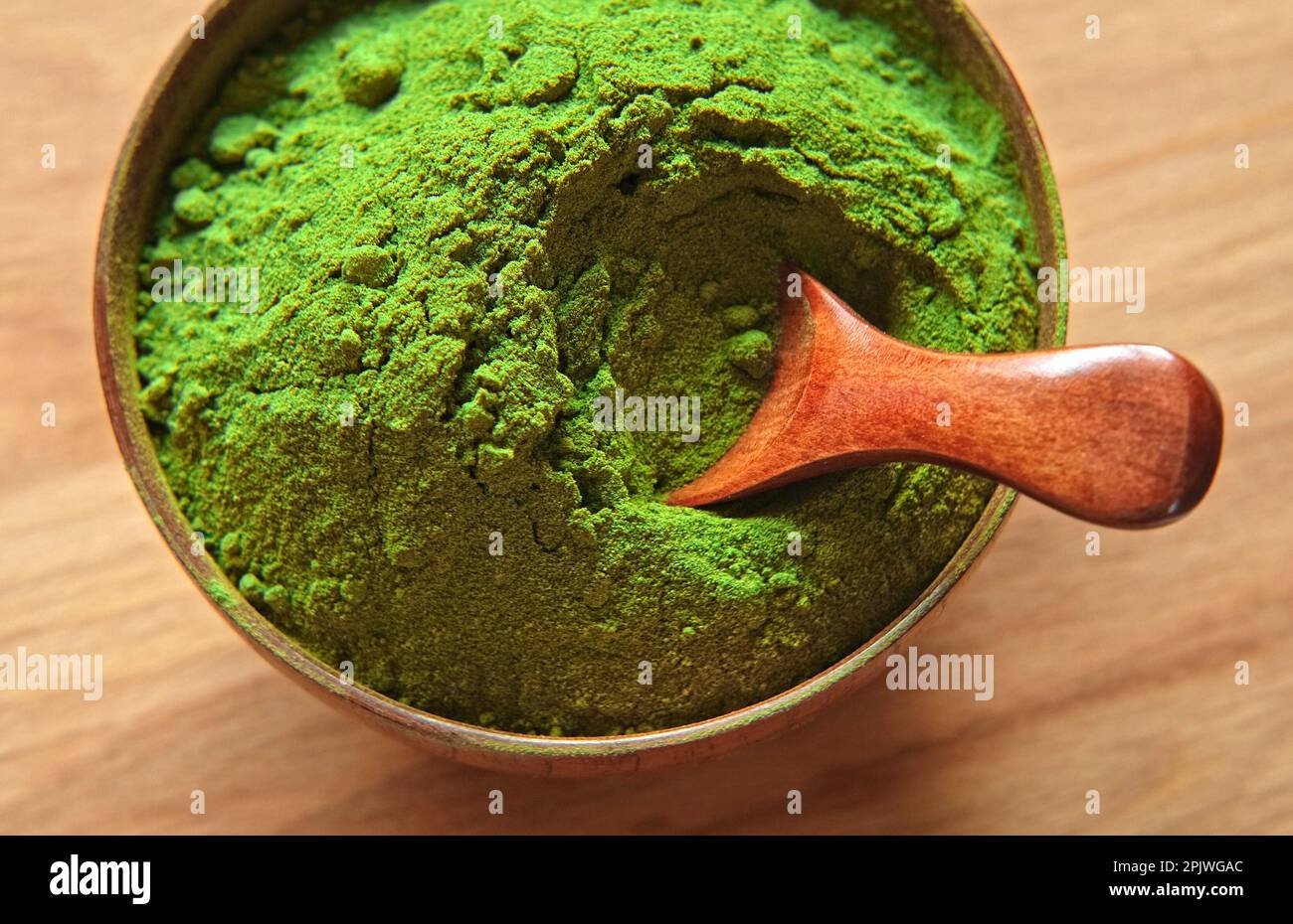Wooden spoon with powdered matcha tea in a bowl spinning on natural ...