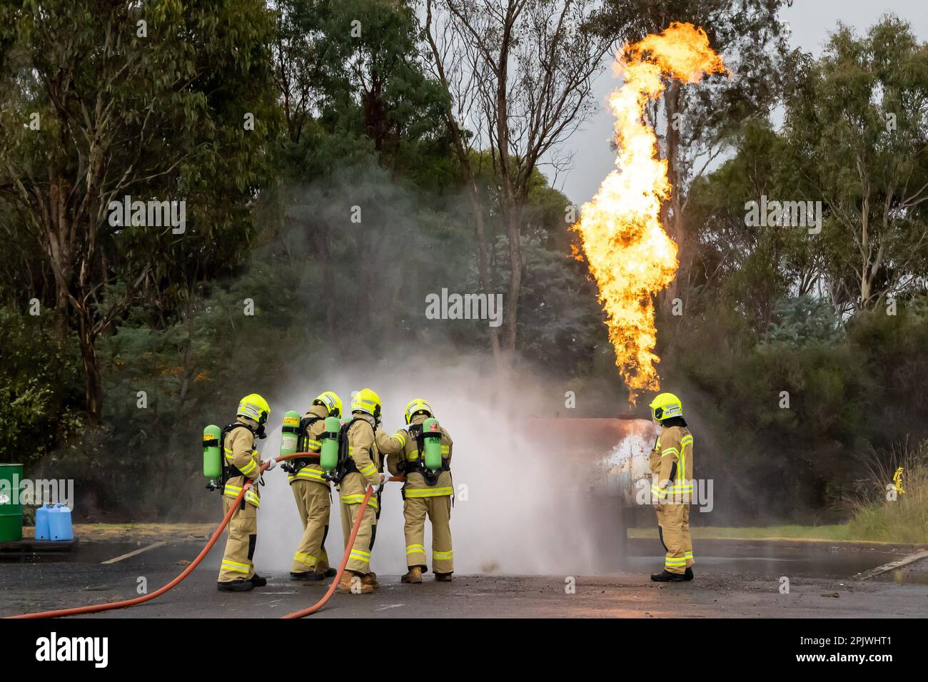 A group of firefighters in a parking lot are engaged in extinguishing ...