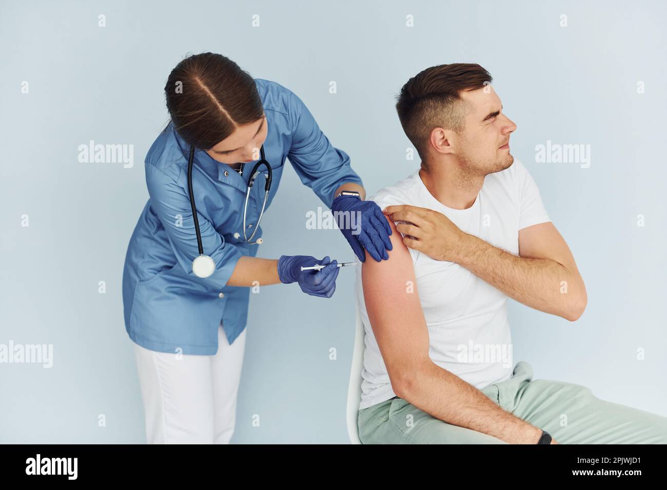 Using syringe. Doctor in uniform making vaccination to the patient ...