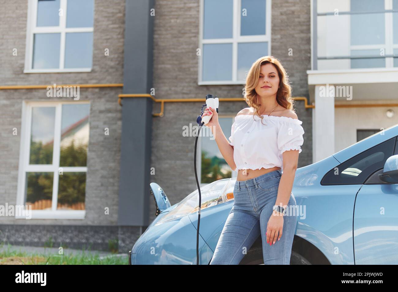 Holding charging cable. Young woman in casual clothes with her ...