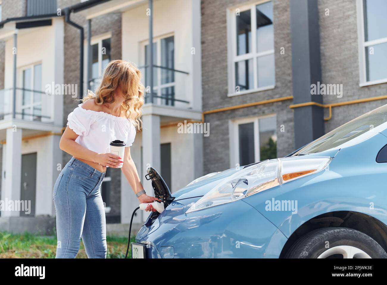 Automobile is charging. Young woman in casual clothes with her ...