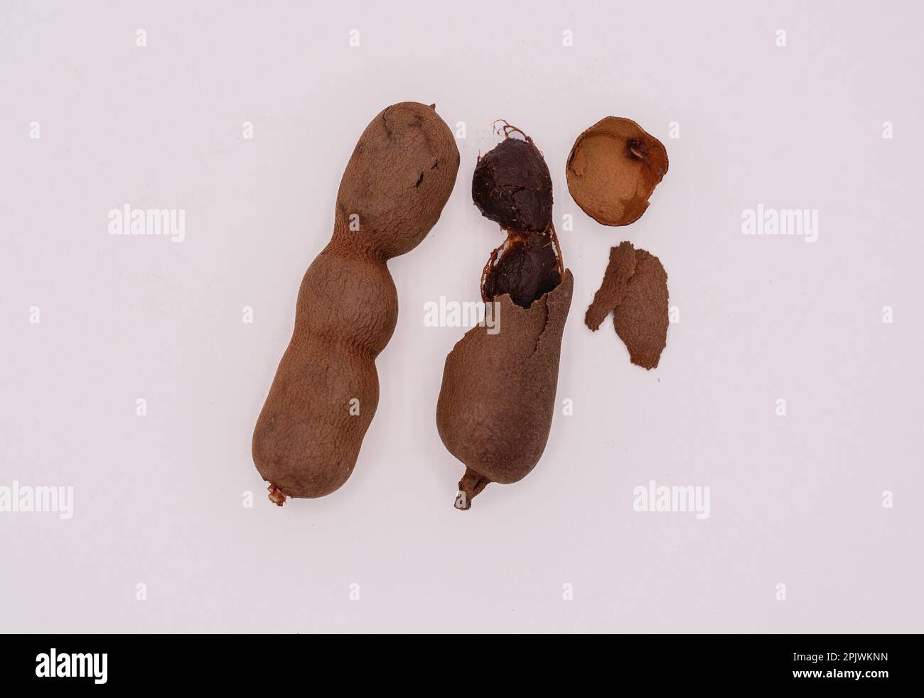 Close-up of 2 tamarind fruits, peeled and unpeeled on isolated white ...