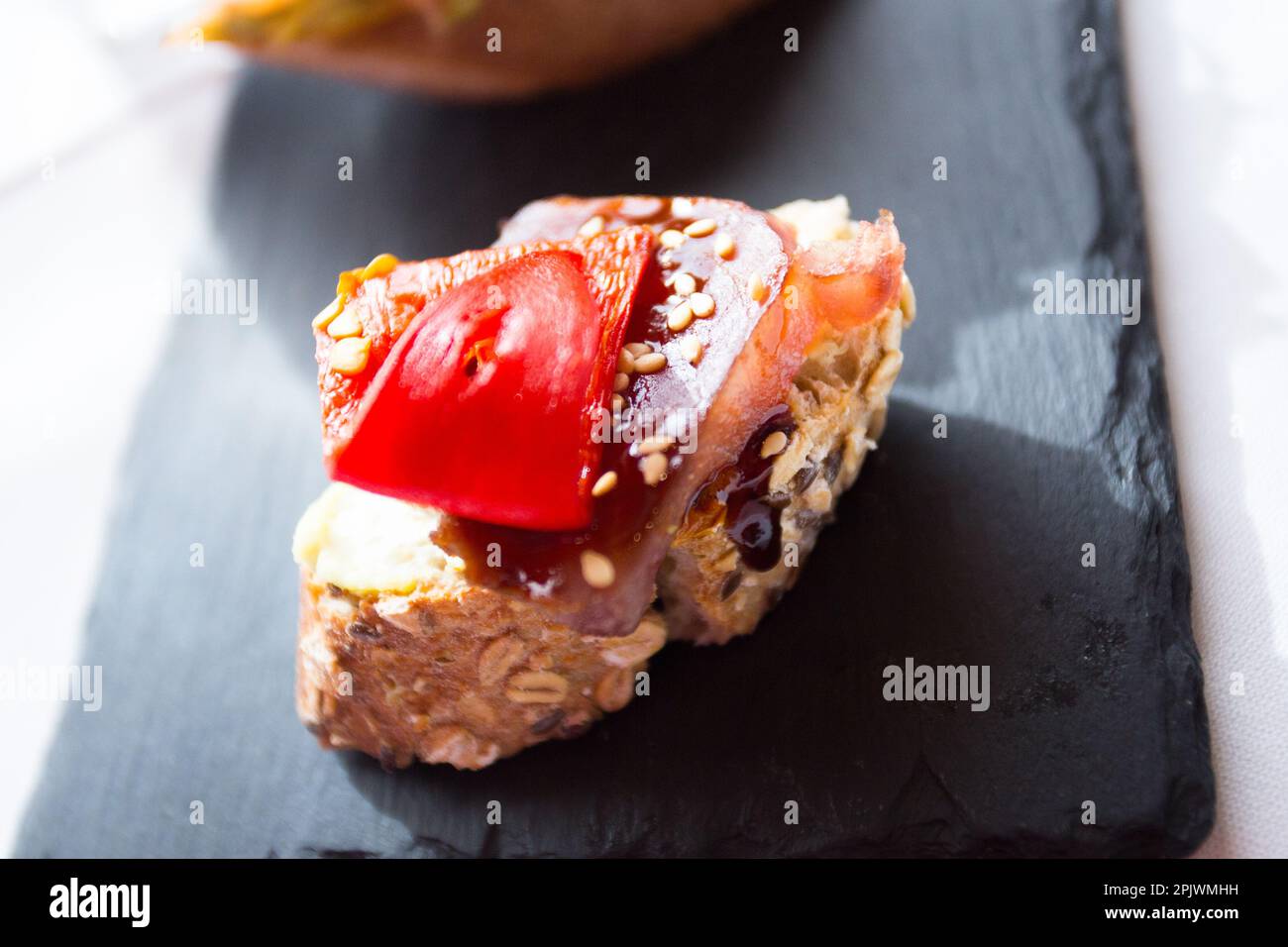 Ham and pepper tapa. A small slice of bread on which a small portion of ...