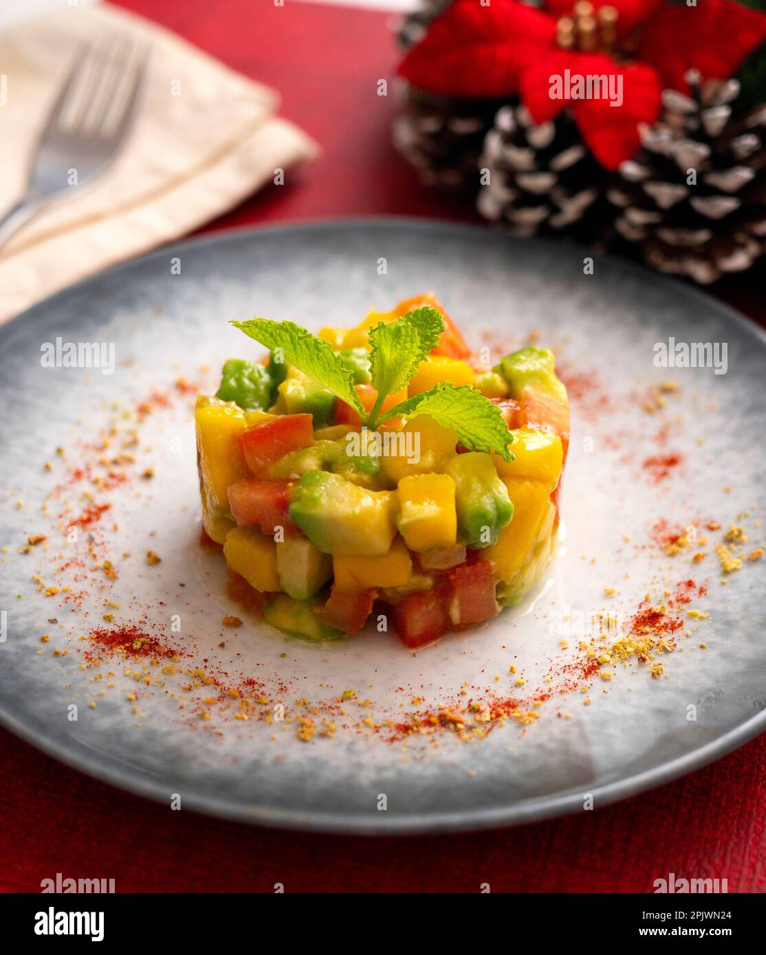Avocado, mango and tomato tartare on a table with Christmas decorations ...
