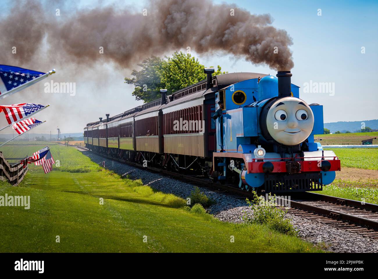 A vintage locomotive is chugging along a railway track, with billowing ...