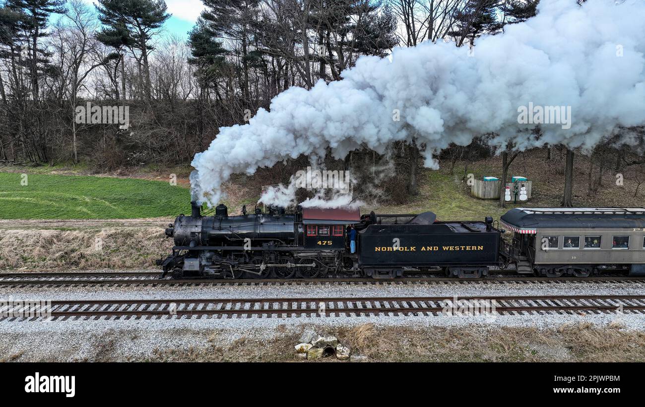 An old-fashioned steam train is travelling along a railway track, with ...
