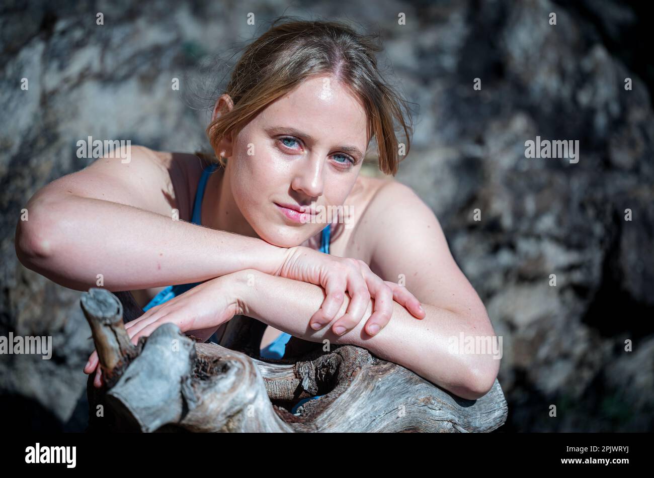 A beautiful woman stands in a sun-drenched outdoor setting, her arm ...