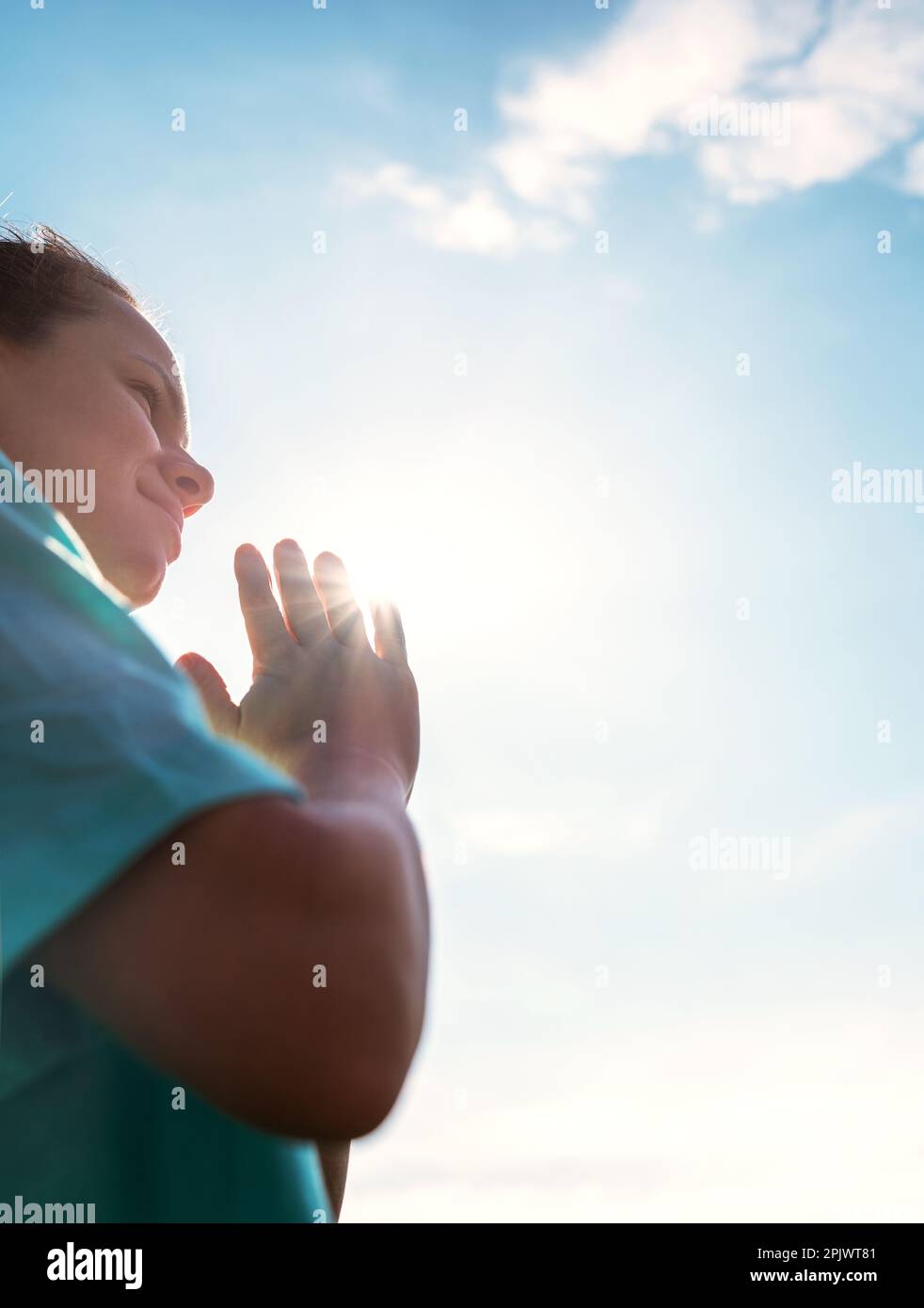 Brunette woman pay respect with Thai wai gesture against blue sky and ...