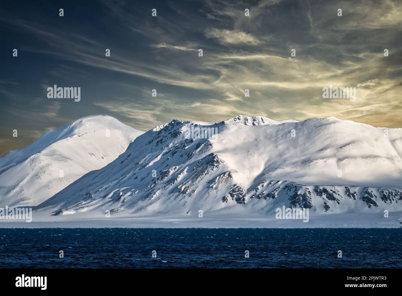 SNOW COVERED SHARP PEAKS WITH SOME ROCK EXPOSED IN THE ARCTIC WITH A ...