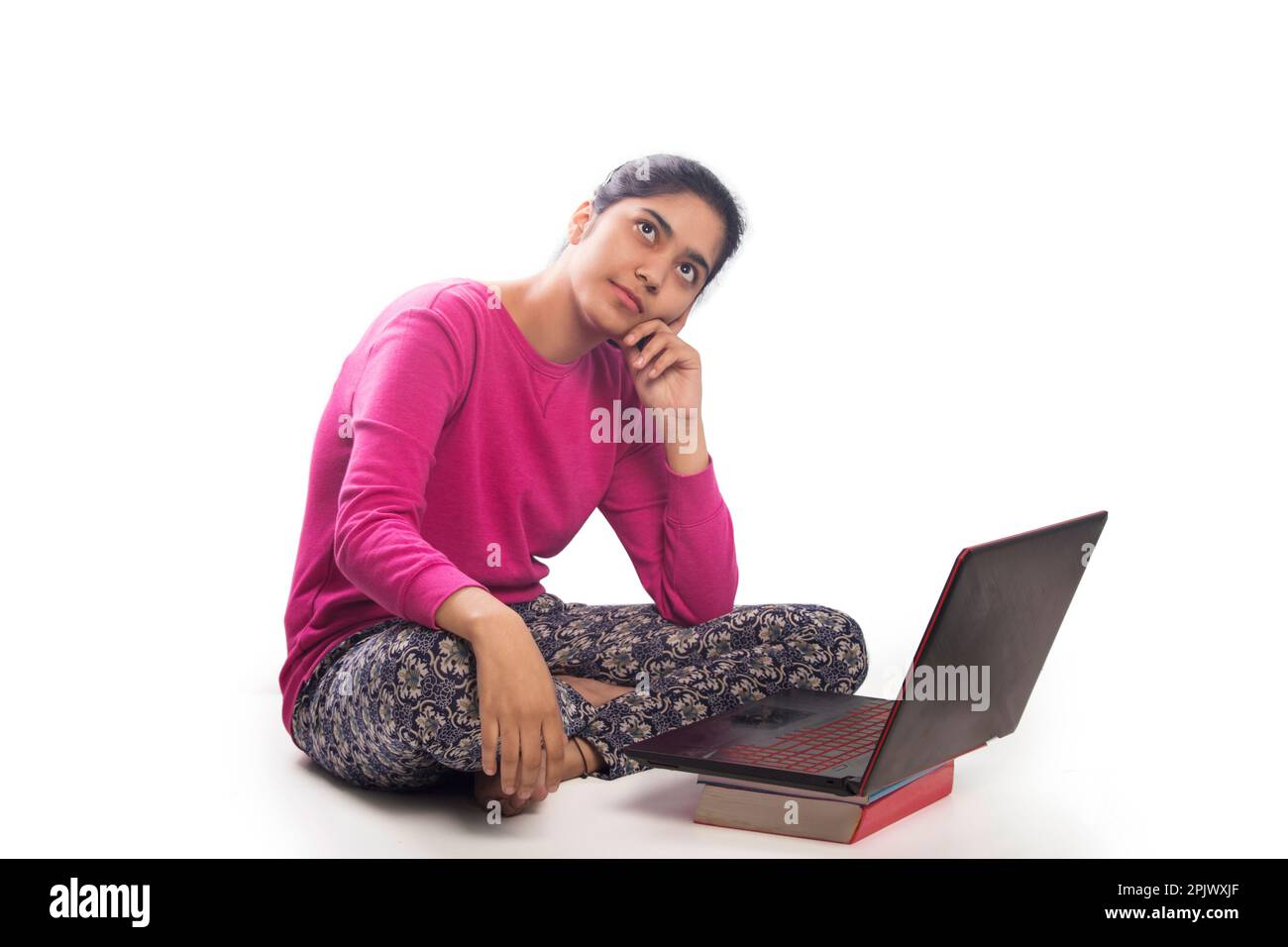 Young Girl looking away and thinking while studying with laptop and ...