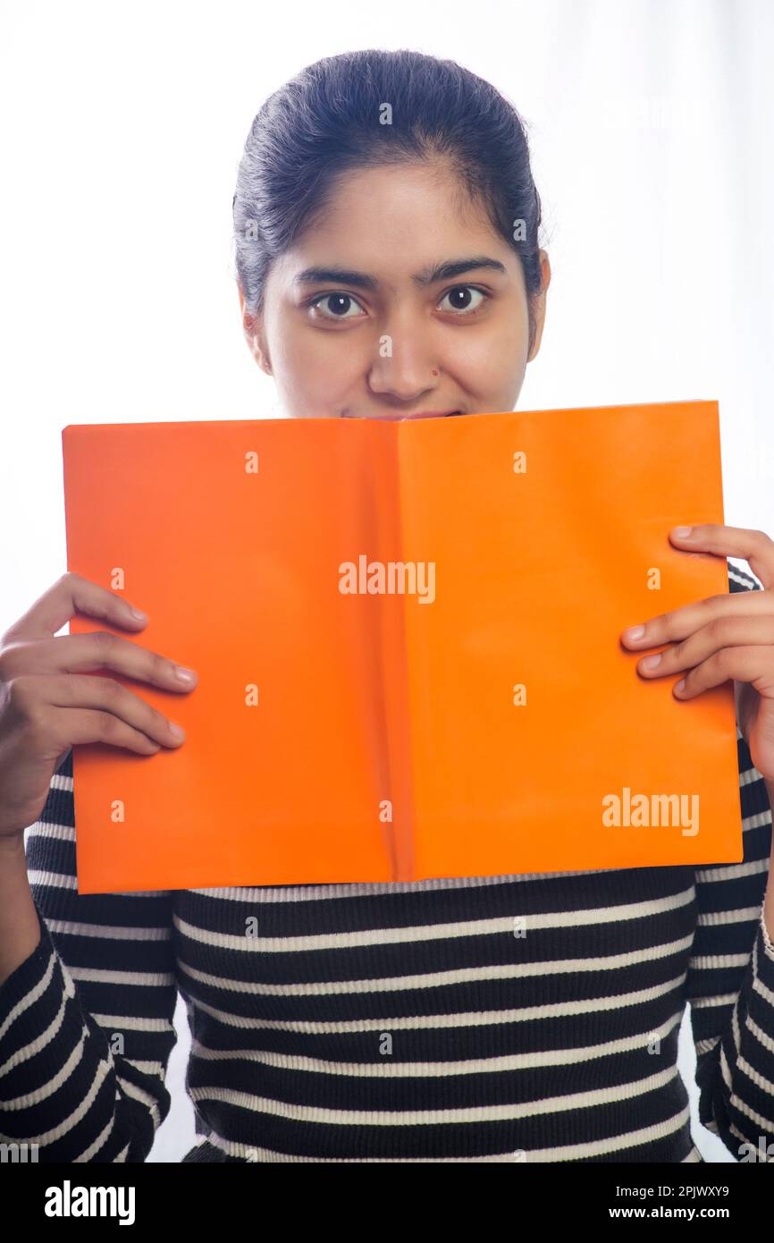 Portrait of girl reading book against white background Stock Photo - Alamy