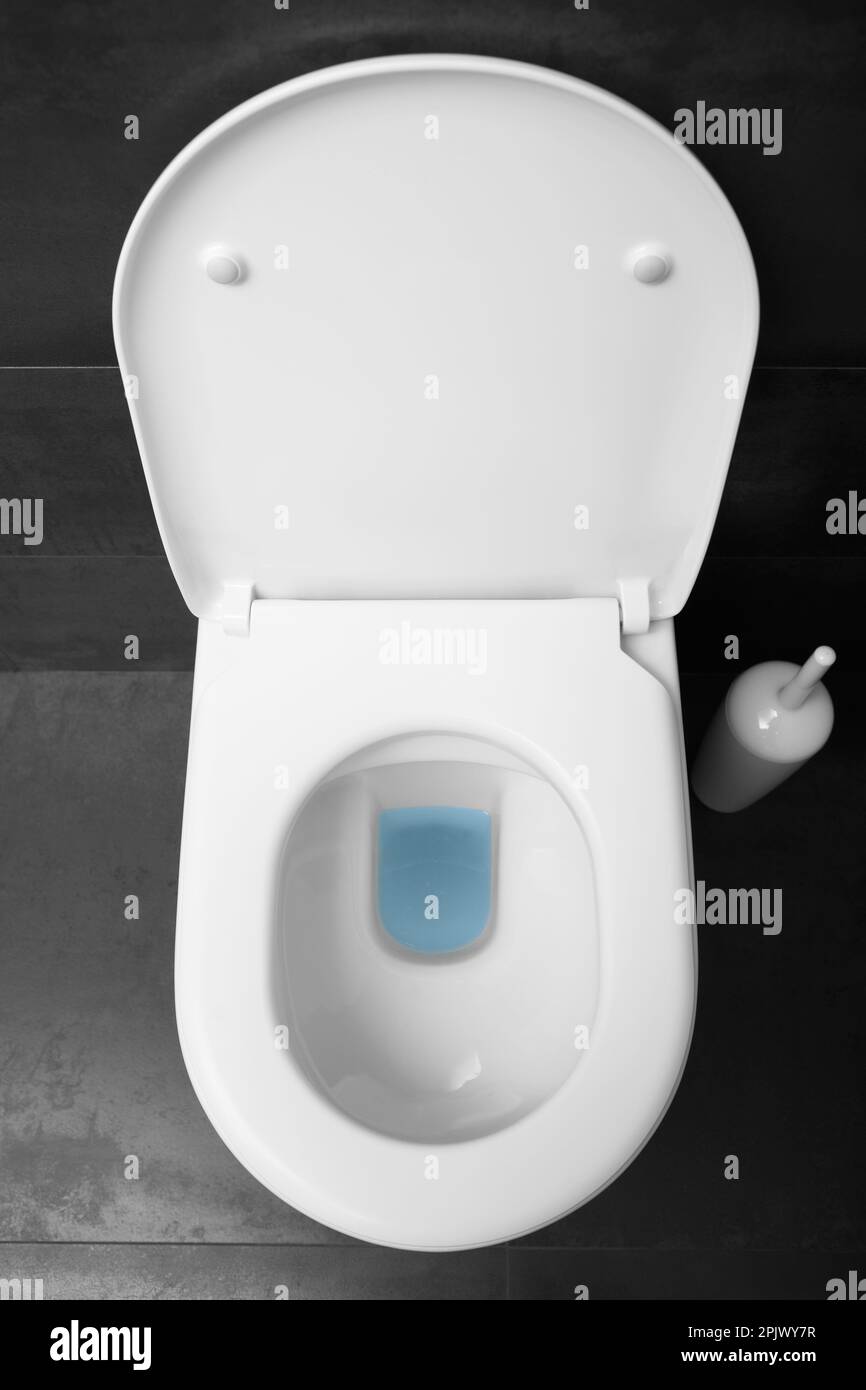 Top view of a white toilet bowl with a raised lid against a black ...