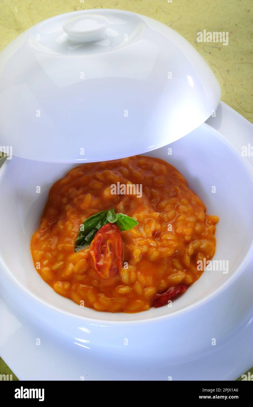 A dish of tomato risotto garnished with a basil leaf Stock Photo - Alamy