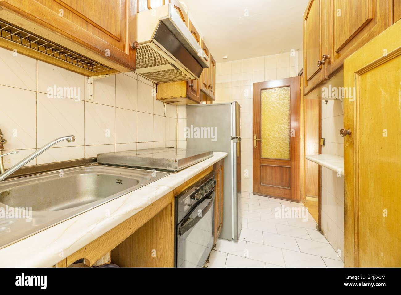 A very used and worn apartment kitchen with very dilapidated wooden ...
