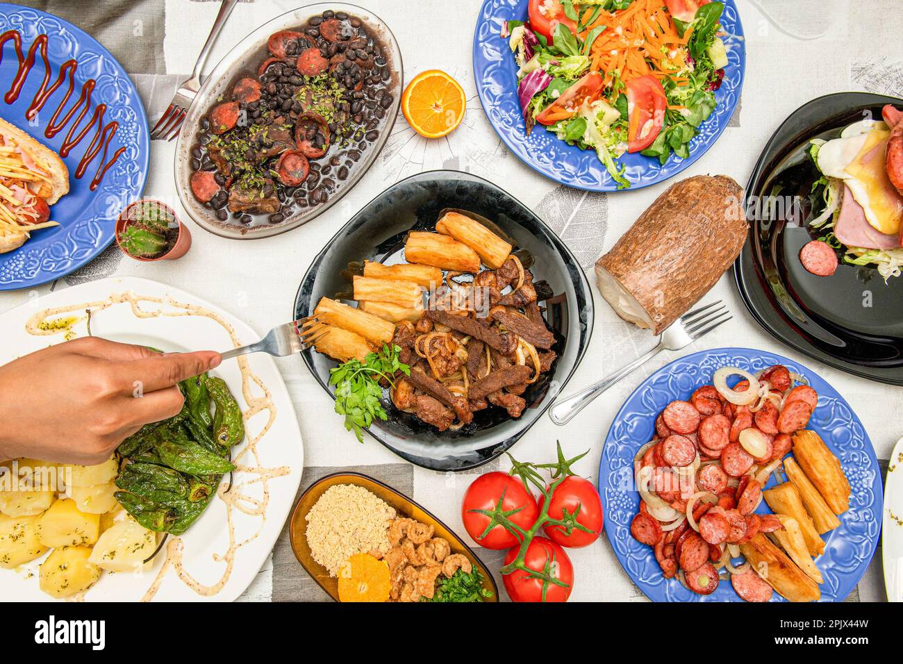 Hand with fork cutting food from exposed plates of typical Brazilian ...