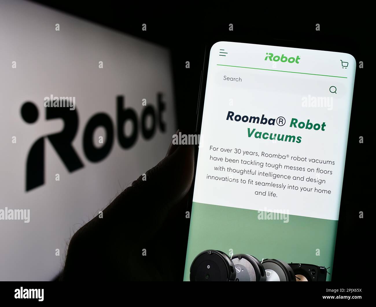 Person holding smartphone with web page of US technology company iRobot ...