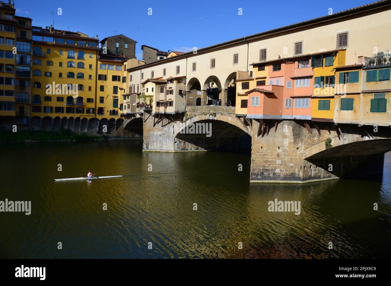 People rowing under the Ponte Vecchio bridge over the Arno, the river ...