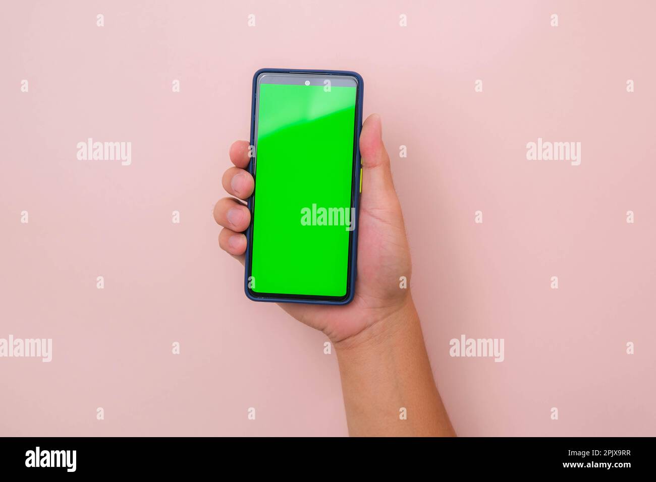 Human hand holding mobile smartphone with green screen in vertical ...