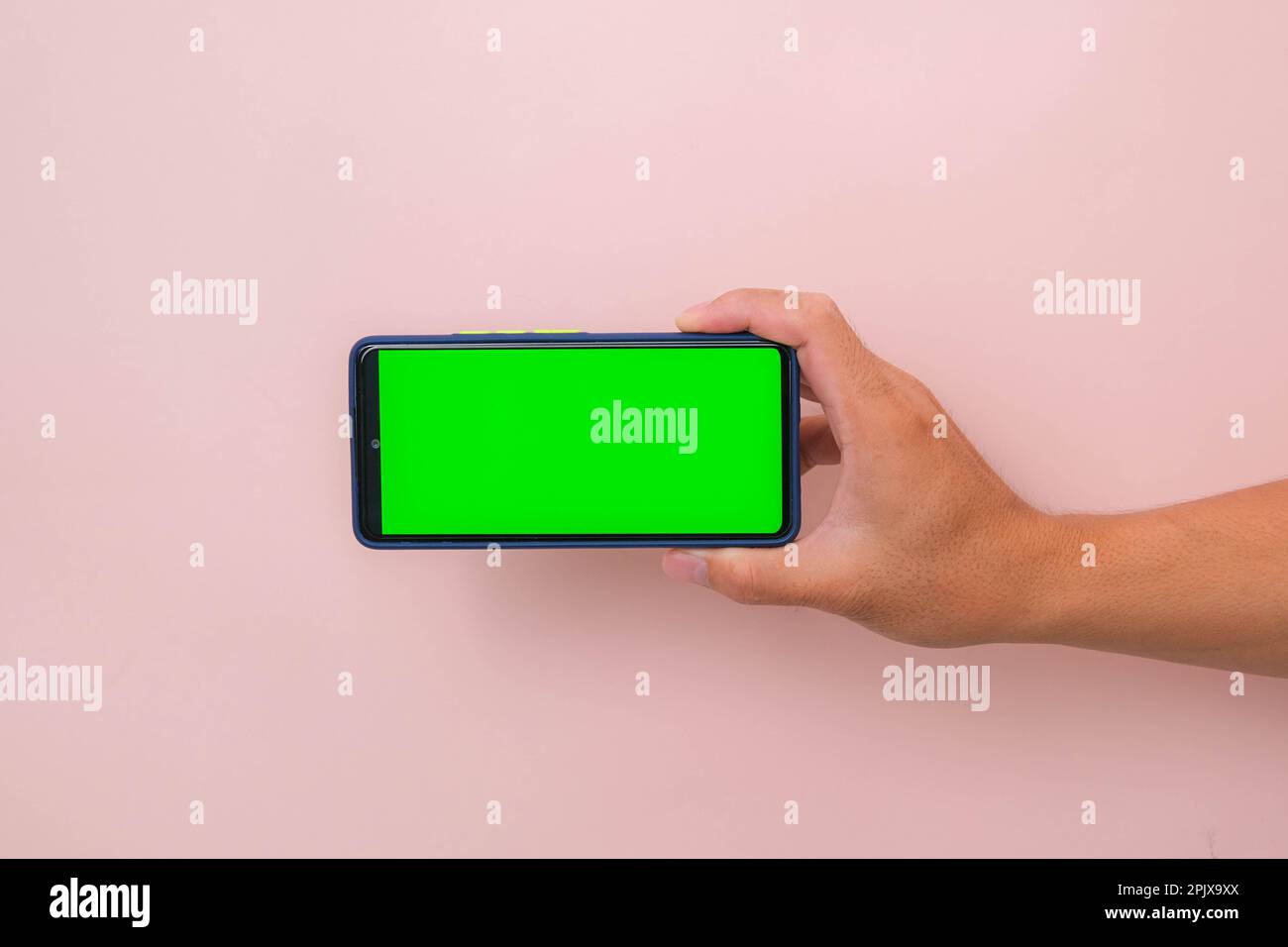 Human hand holding mobile smartphone with green screen in horizontal ...