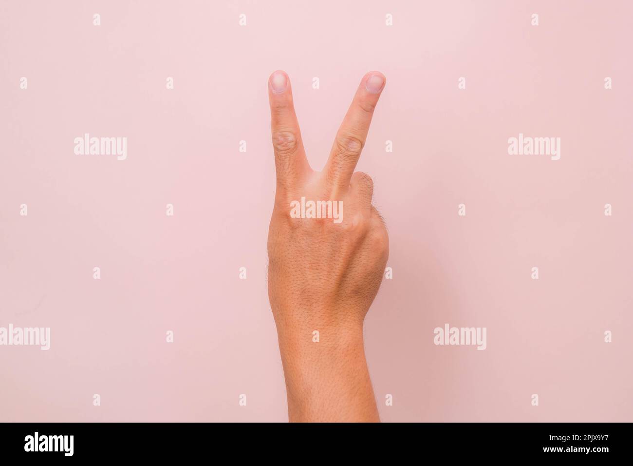 Hand showing two fingers gesture (peace sign) isolated on pink ...