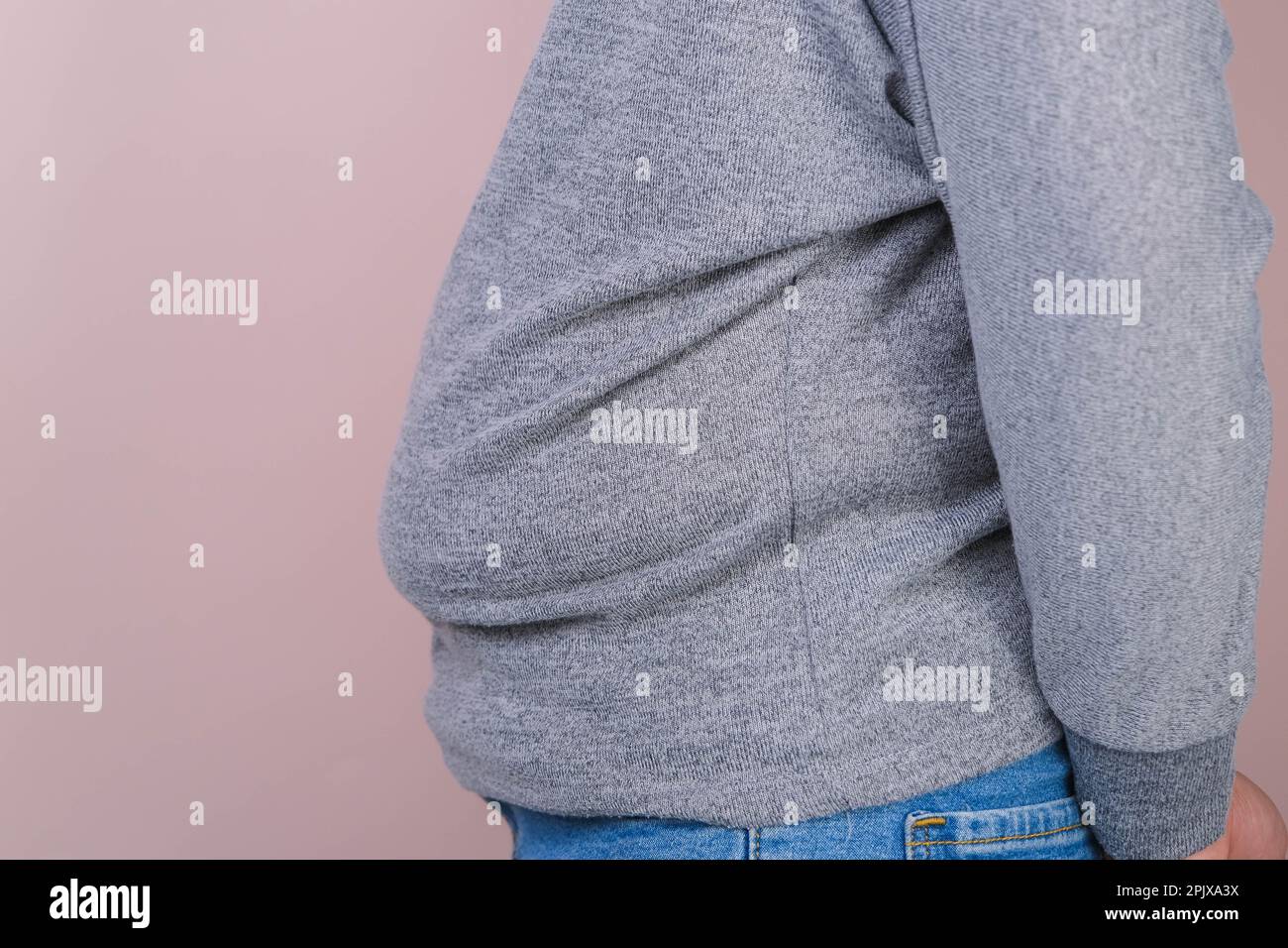Fat woman hand holding excessive belly fat isolated on pink background ...
