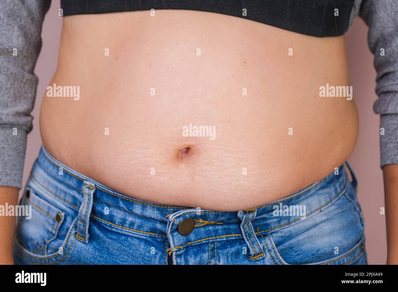 Fat woman hand holding excessive belly fat isolated on pink background ...
