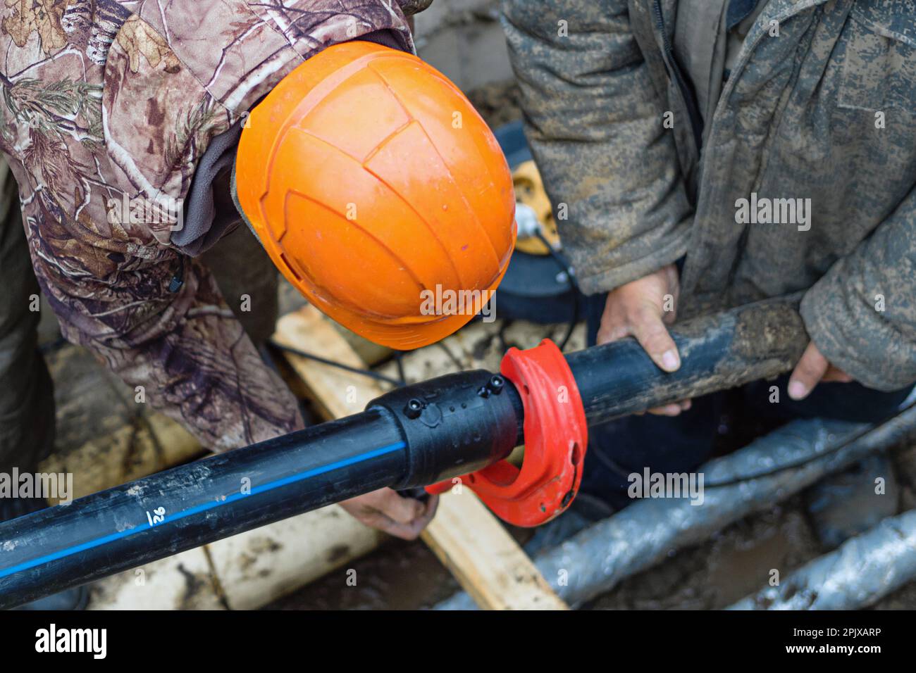 Worker in helmet repairs communal water pipe in trench on street. Work ...