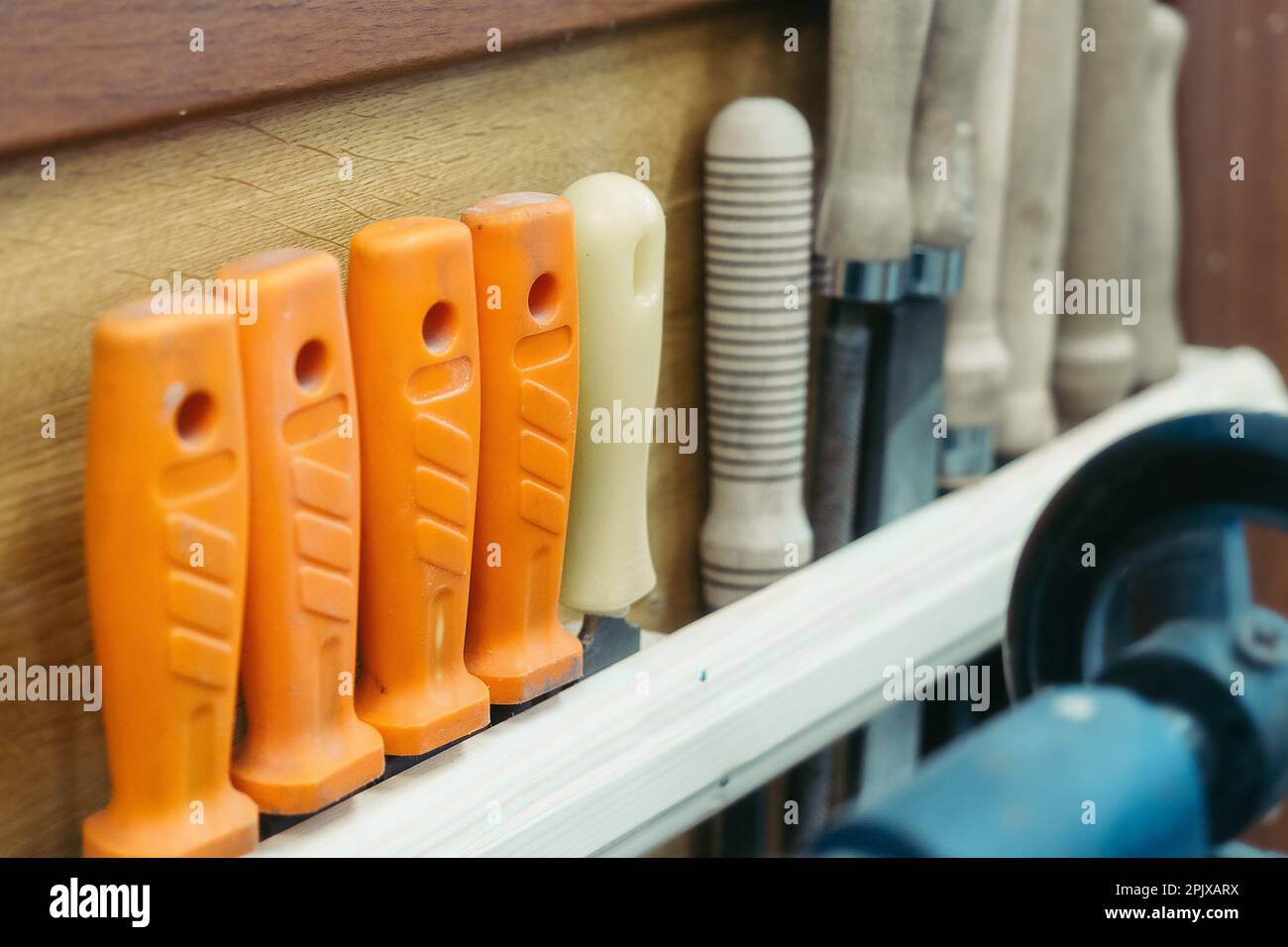Carpentry tools hang on wall next to workbench. Close-up. Storage of ...