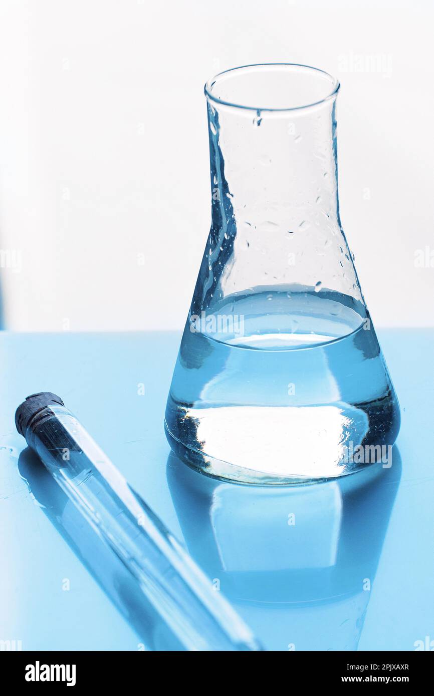 Glass medical test tube and liquid flask stand on mirror table ...