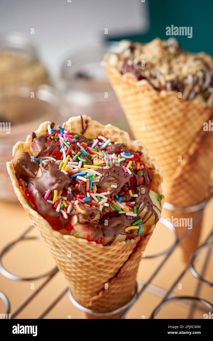 A waffle cone with fruits inside coated in creamy chocolate with ...