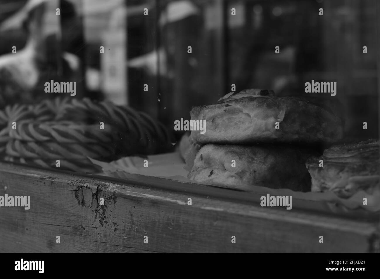 Black and white photograph of a freshly-baked pastry in a glass display ...