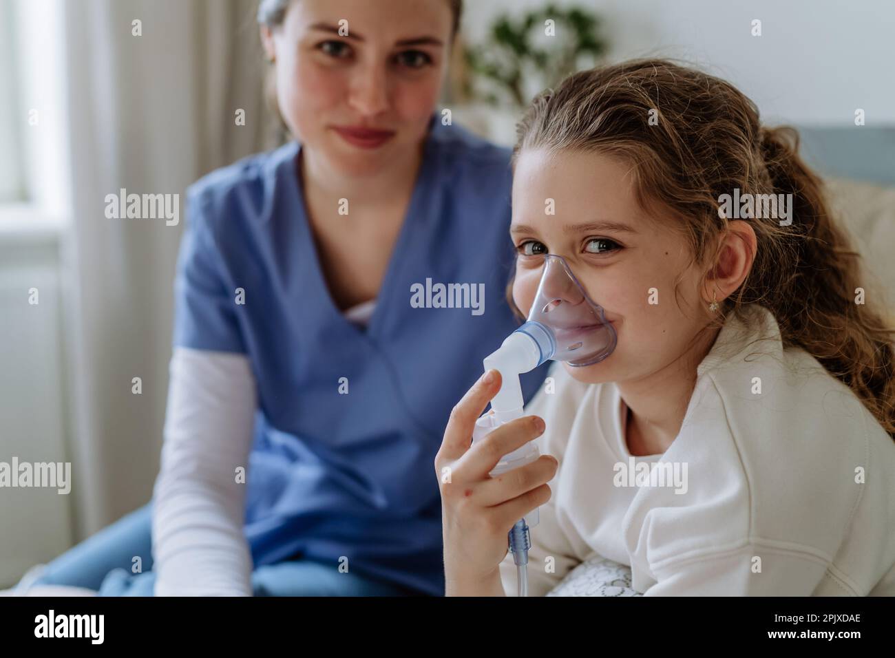 Little girl with inhaler in hospital room, nurse chcecking her Stock ...