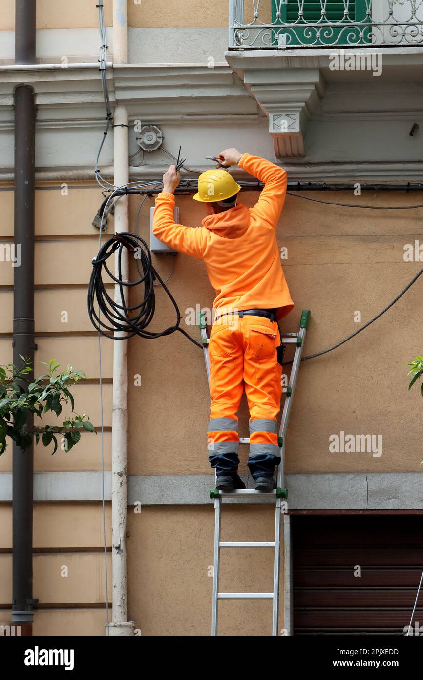 Telephone network worker on a ladder repairs internet network cables ...