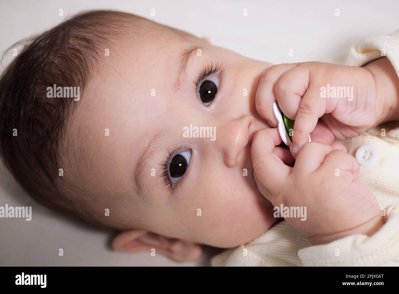Baby sucking Pacifier looking on bed. portrait of cute newborn baby ...