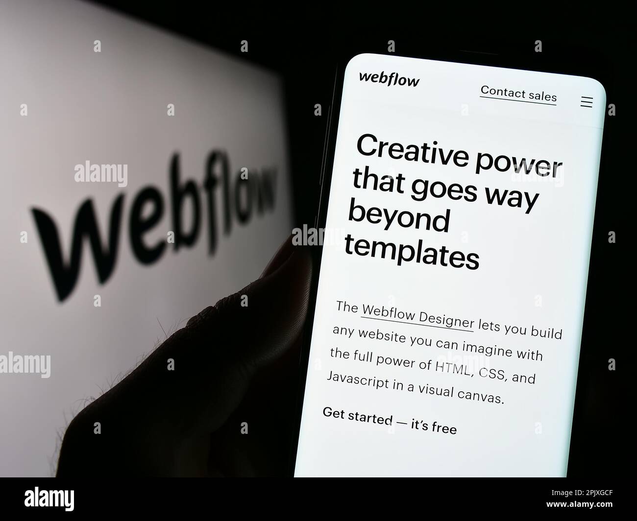 Person holding cellphone with webpage of US web development software ...