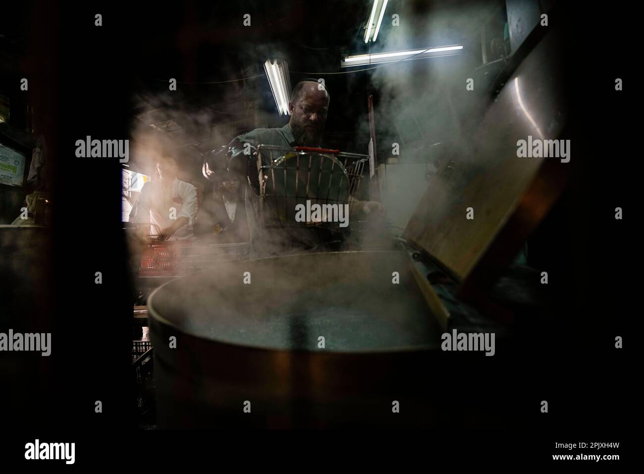An ultra-Orthodox Jewish man dips cooking utensils in boiling water to ...
