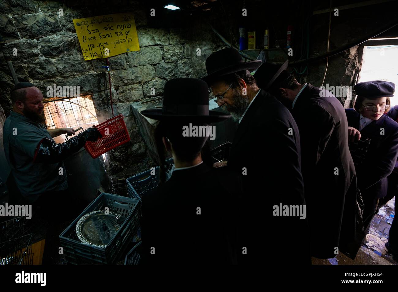 An ultra-Orthodox Jewish man dips cooking utensils in boiling water to ...