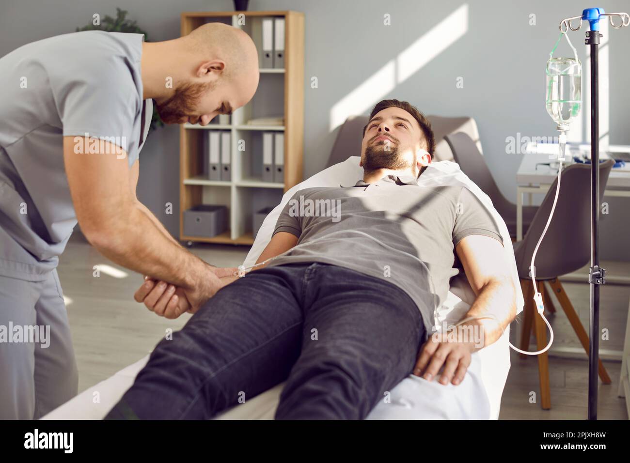 Nurse puts intravenous vitamin infusion catheter in vein of young male ...