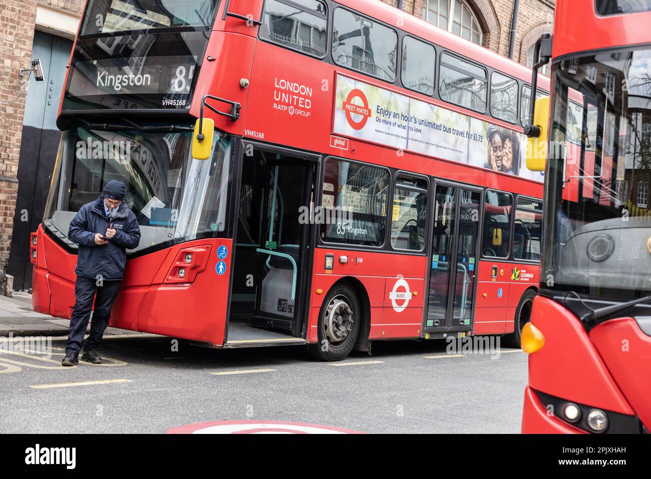 London bus driver taking a break whilst having a Vape as he leans on ...