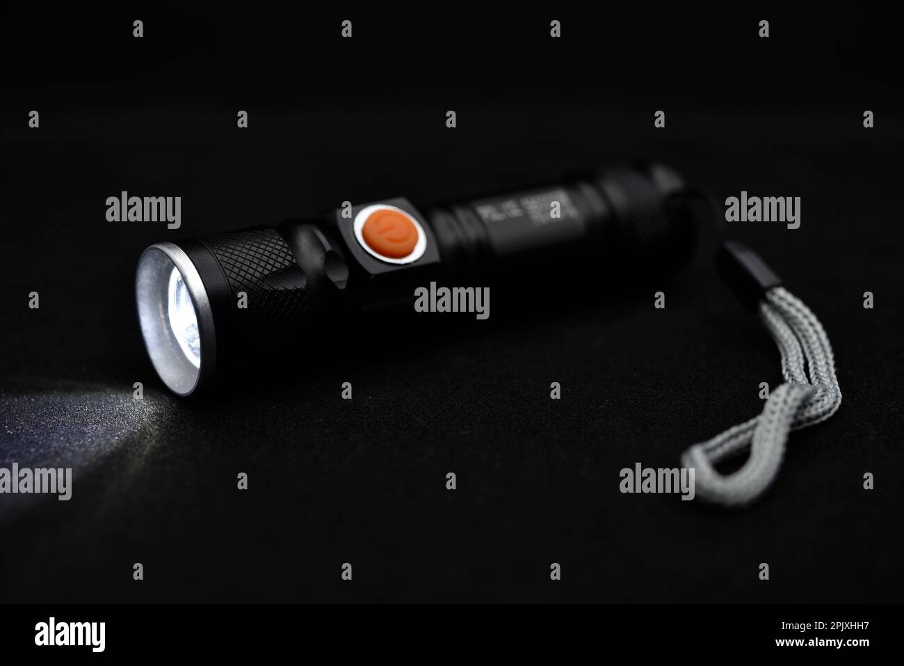 Metal black flashlight on a black background. Burning pocket flashlight ...