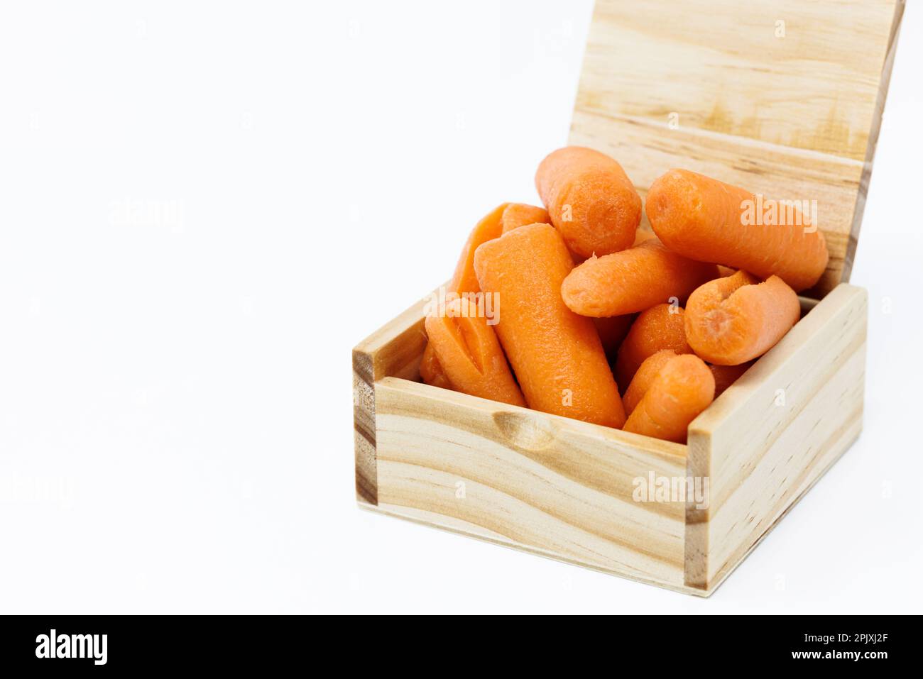 A wooden box with its lid open, full of fresh baby carrots isolated on ...