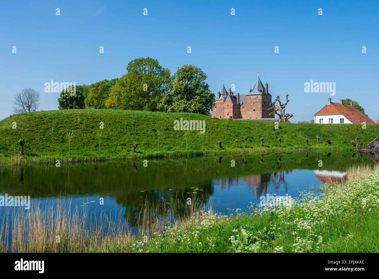 Captivating view across the moat water over the dike to Slot Loevestein ...