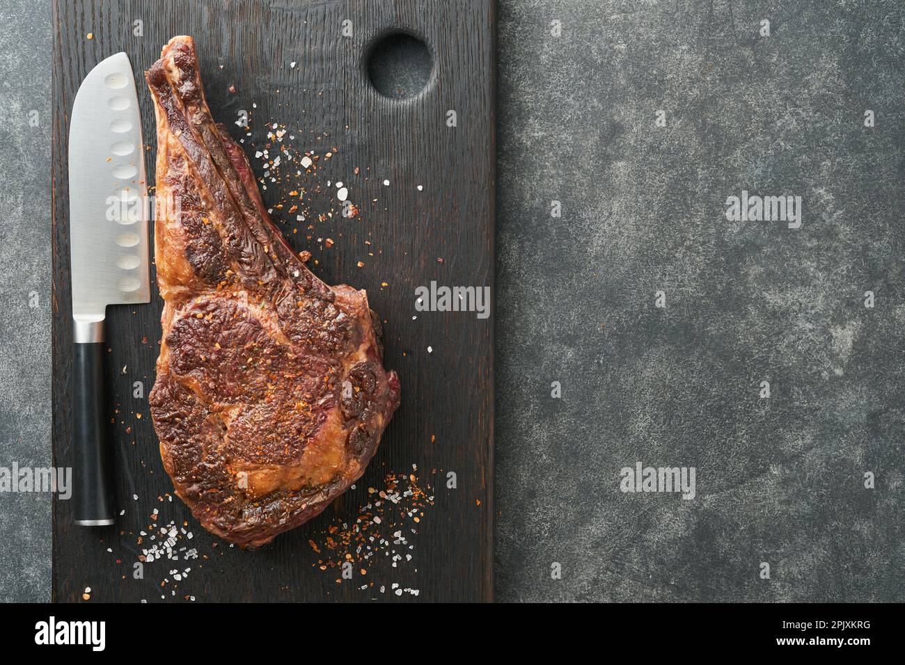 Tomahawk steak. Sliced grilled tomahawk beef steak with baked cherry ...