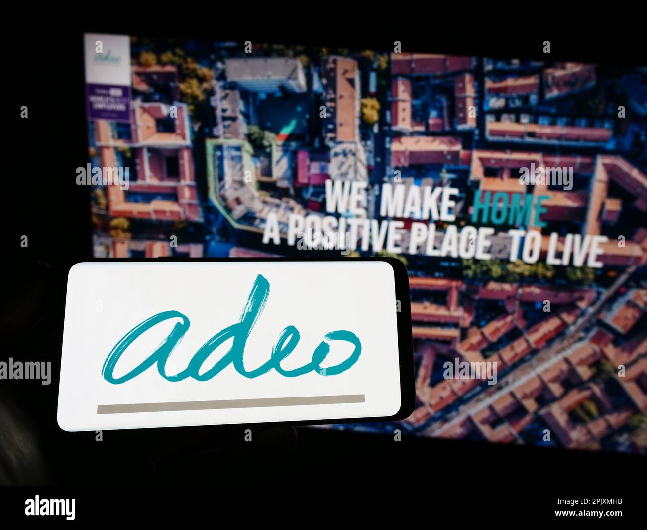 Person holding smartphone with logo of French retail company Adeo S.A ...