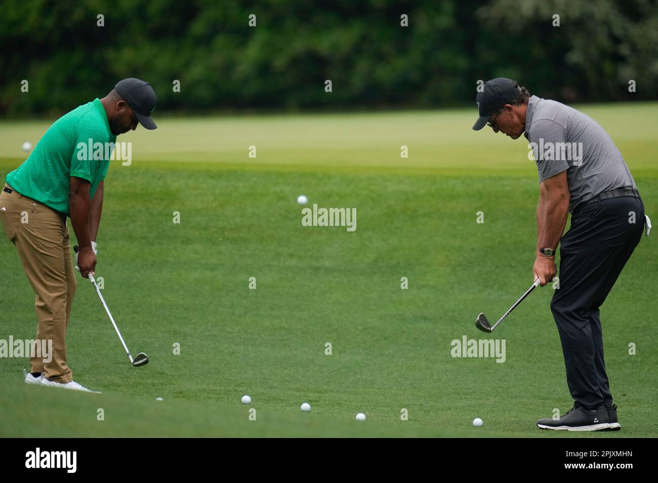 Harold Varner III, left, and Phil Mickelson chip to the 11th green ...