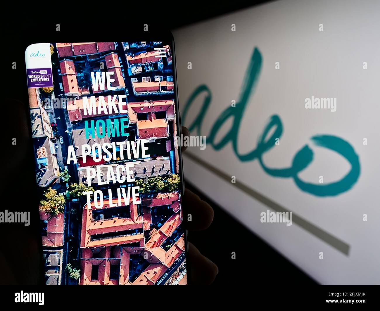 Person holding mobile phone with website of French retail company Adeo ...