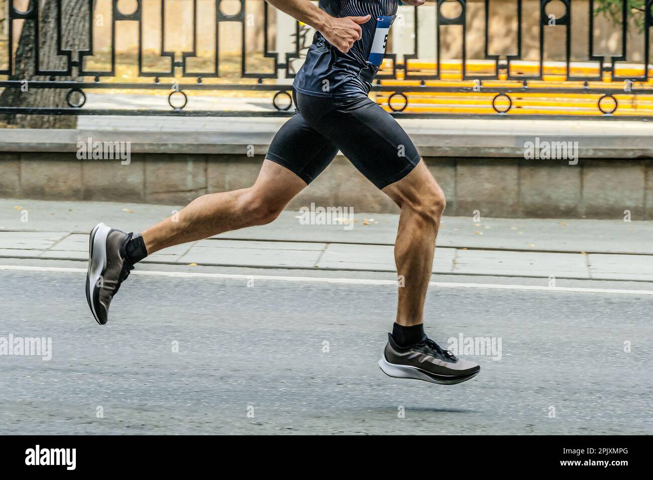 male runner in black tights running city marathon, muscular legs of ...