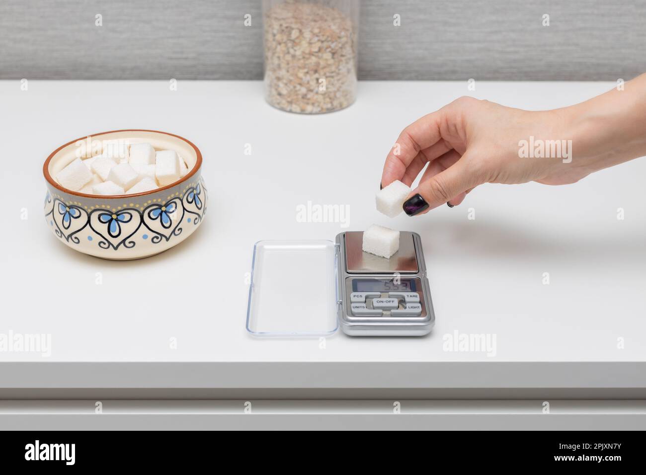 man weighing a cube of sugar on a small scale. scales for small items ...