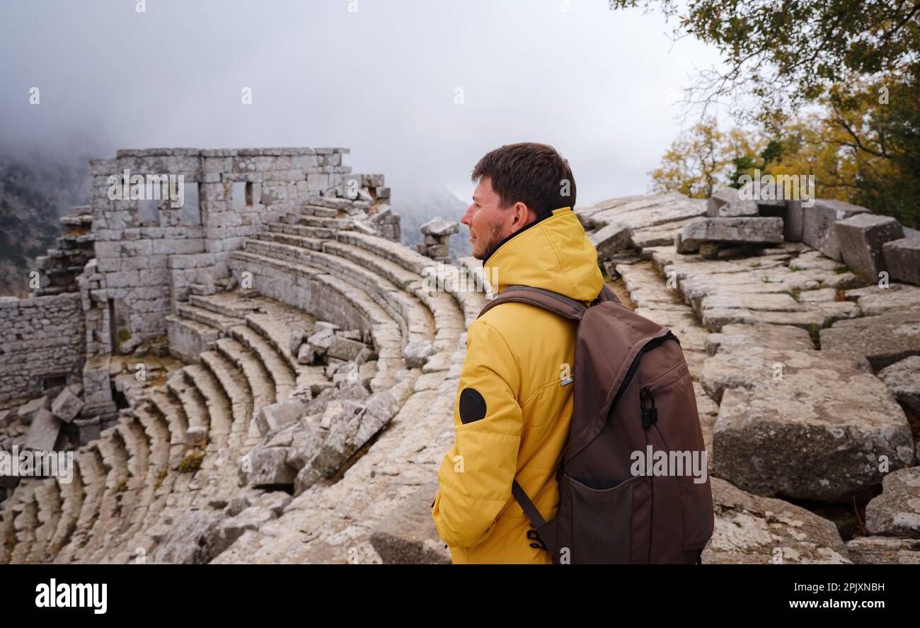 Autumn walk , man in yellow jacket looks at the ancient amphitheatre in ...